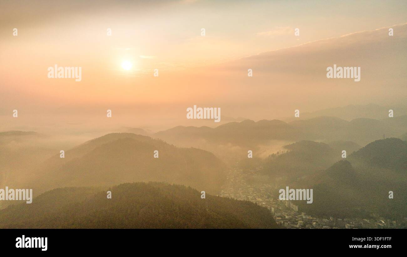 The morning sun rises over mountains as mist lingers in Dingshi Town ...