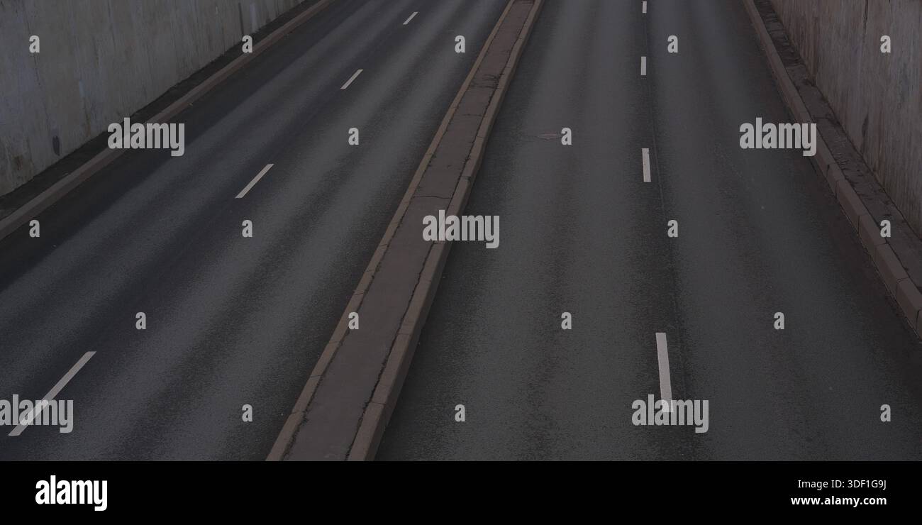 Empty road with lane markings and concrete walls on both sides. City ...