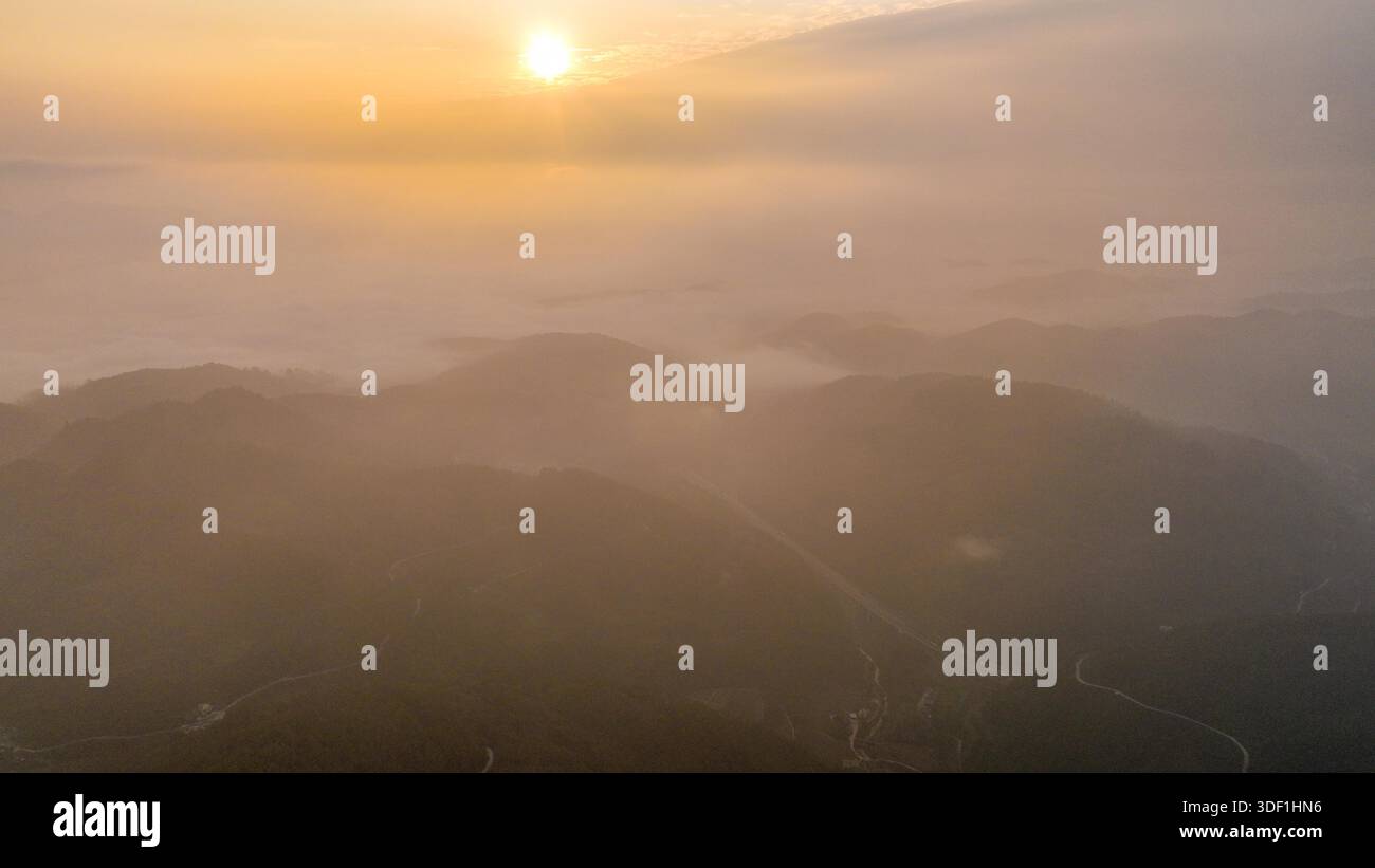 The morning sun rises over mountains as mist lingers in Dingshi Town ...