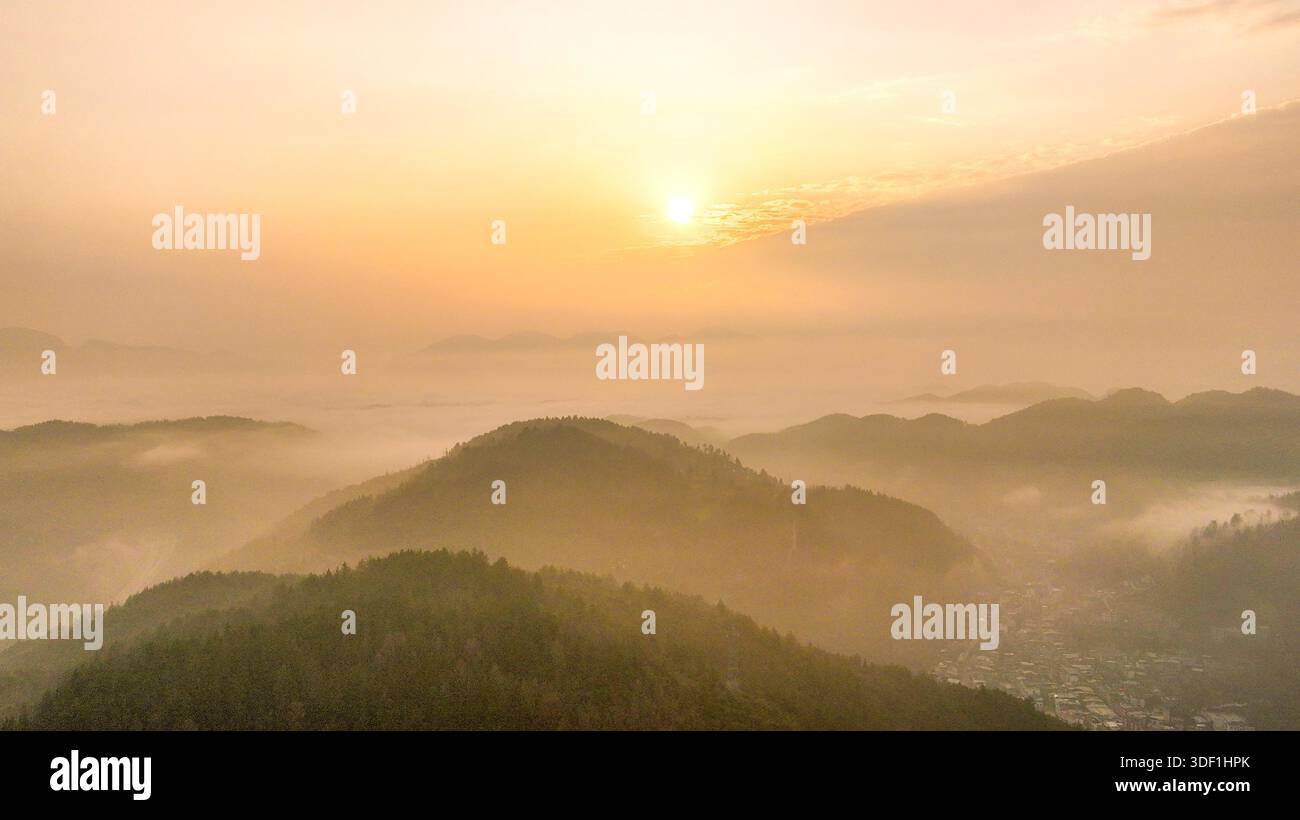 The morning sun rises over mountains as mist lingers in Dingshi Town ...