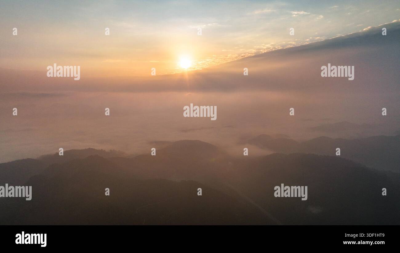 The morning sun rises over mountains as mist lingers in Dingshi Town ...