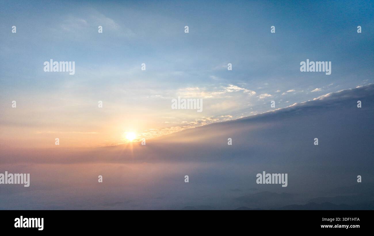 The morning sun rises over mountains as mist lingers in Dingshi Town ...