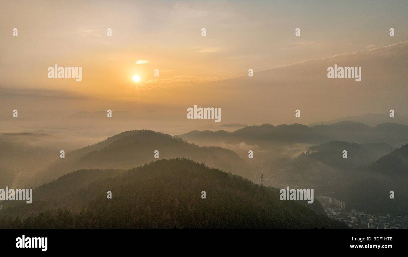 The morning sun rises over mountains as mist lingers in Dingshi Town ...