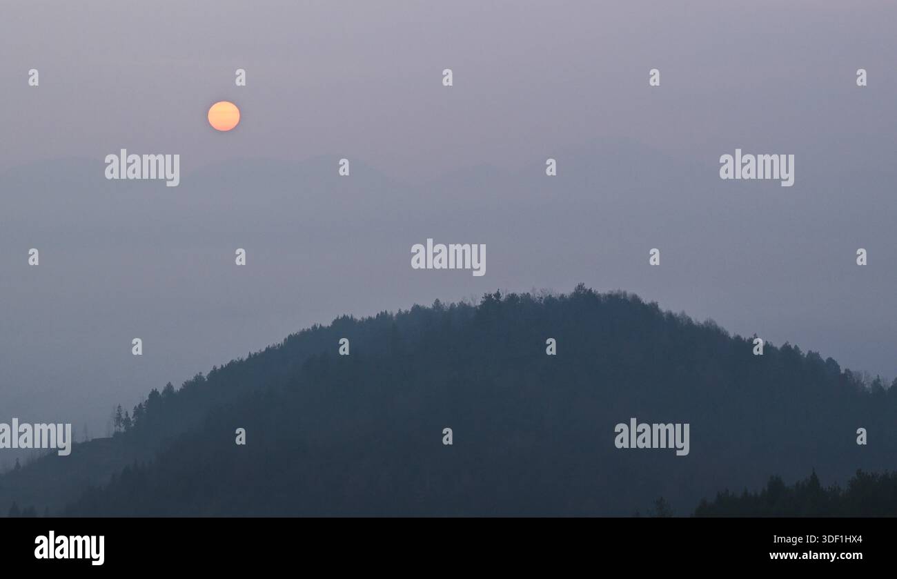 The morning sun rises over mountains as mist lingers in Dingshi Town ...