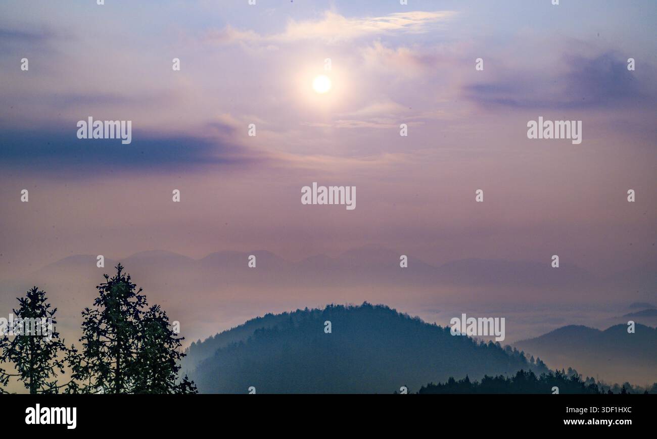 The morning sun rises over mountains as mist lingers in Dingshi Town ...