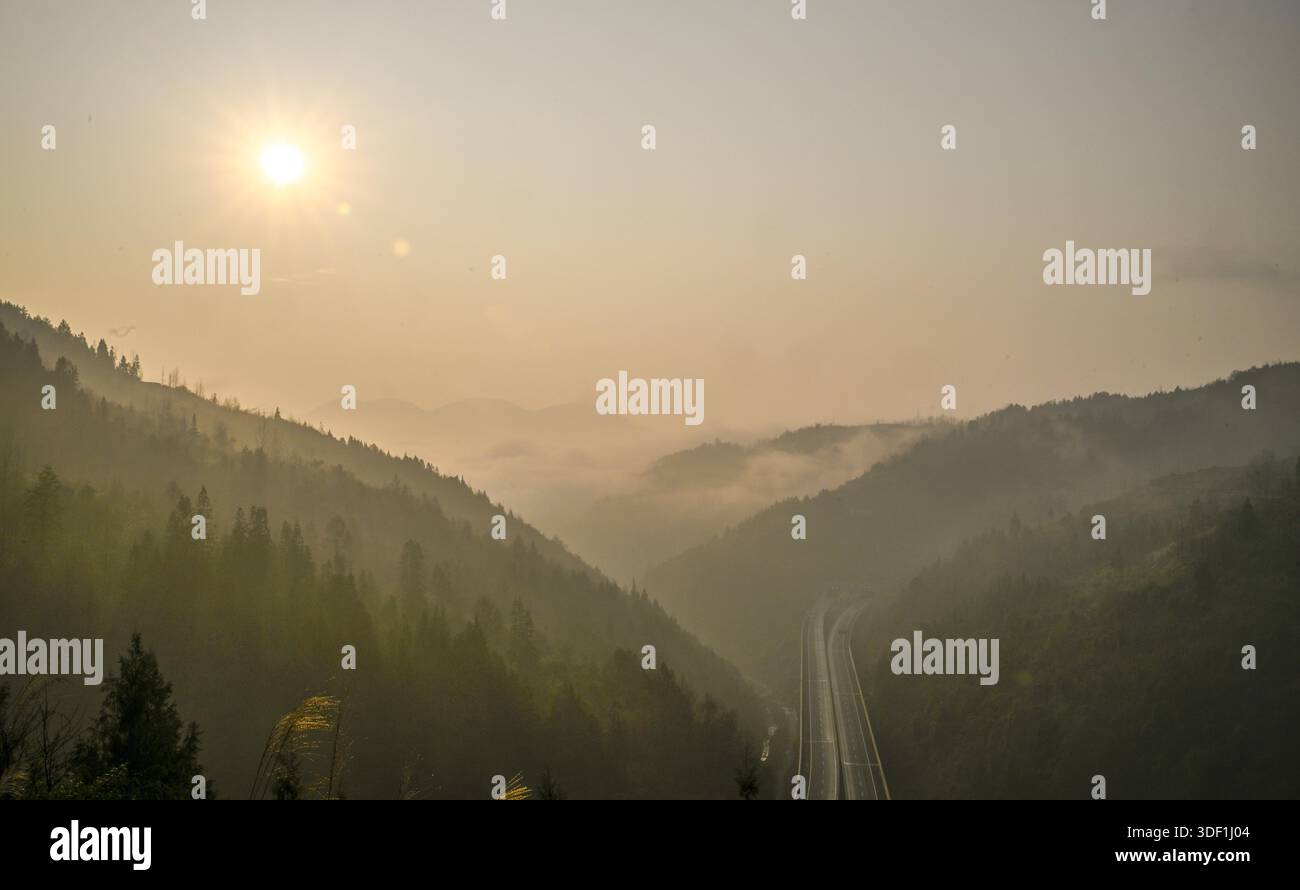 The morning sun rises over mountains as mist lingers in Dingshi Town ...