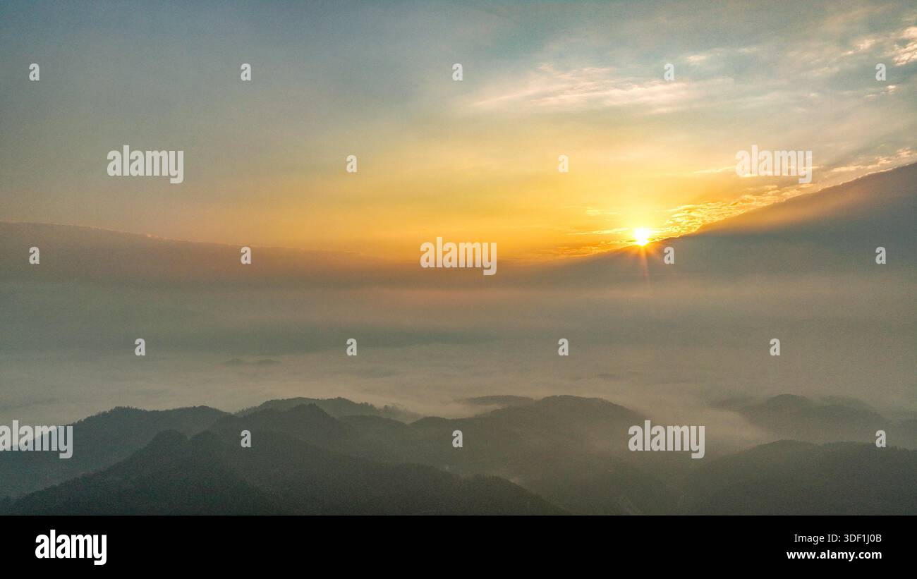 The morning sun rises over mountains as mist lingers in Dingshi Town ...