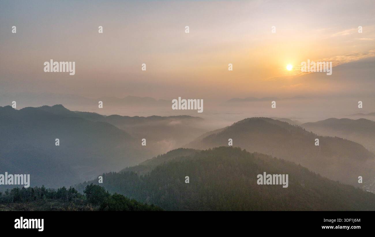 The morning sun rises over mountains as mist lingers in Dingshi Town ...