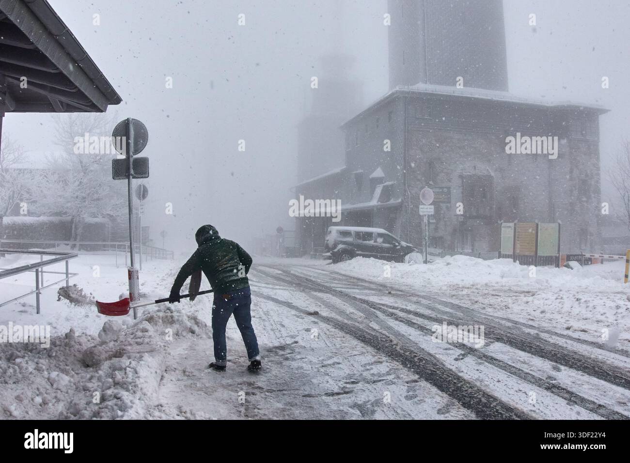 A woman cleans snow from a road on top of the Feldberg mountain near ...