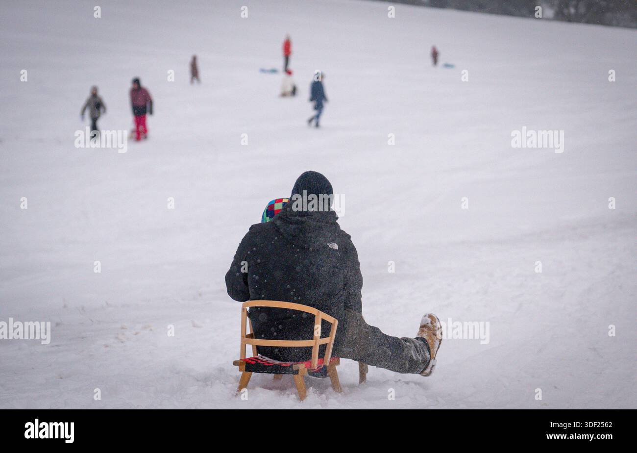 10 January 2026, North Rhine-Westphalia, Adenau: A father tobogganing ...