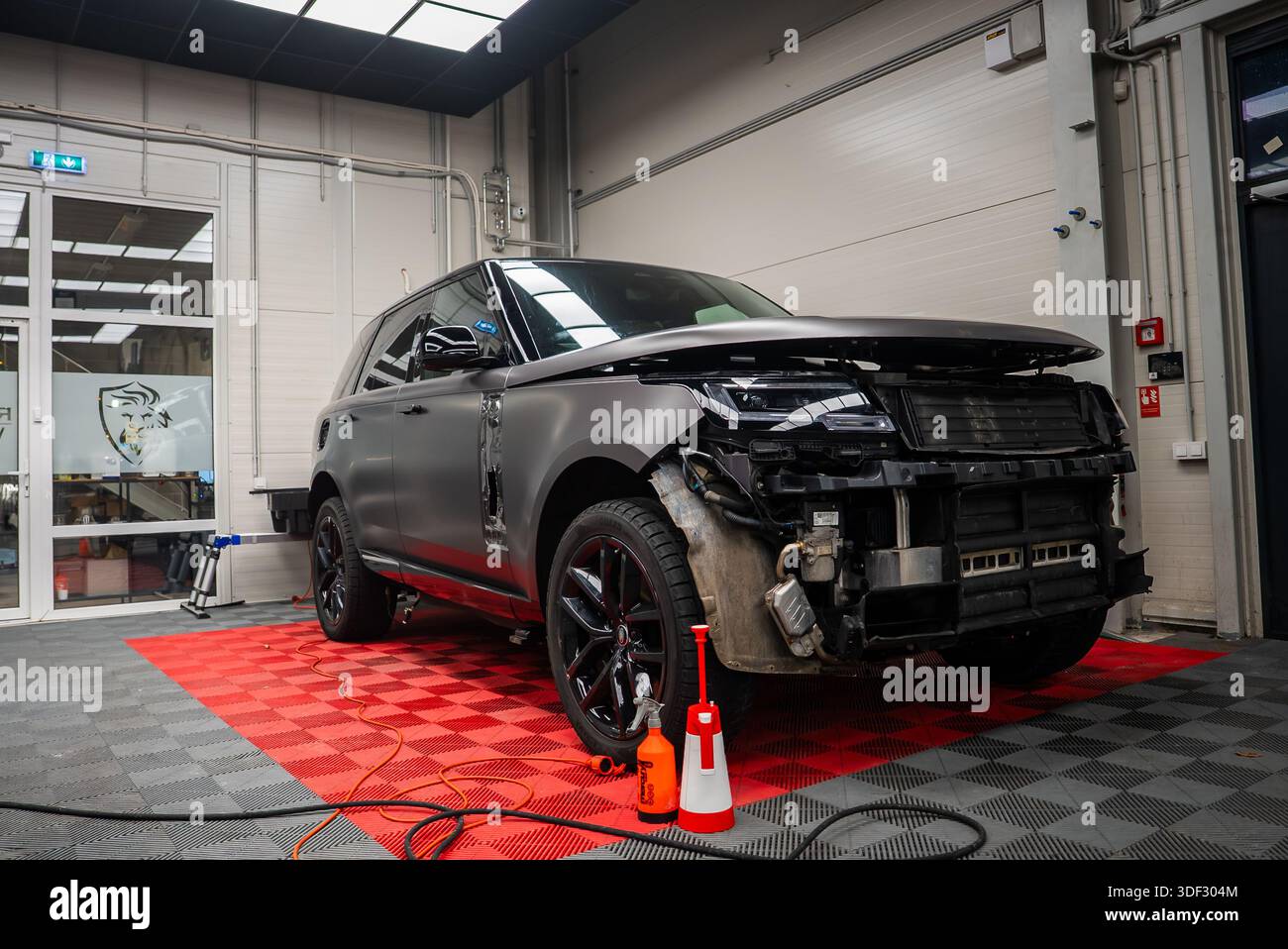 Matte gray Range Rover in repair bay with bumper and fender off Stock ...