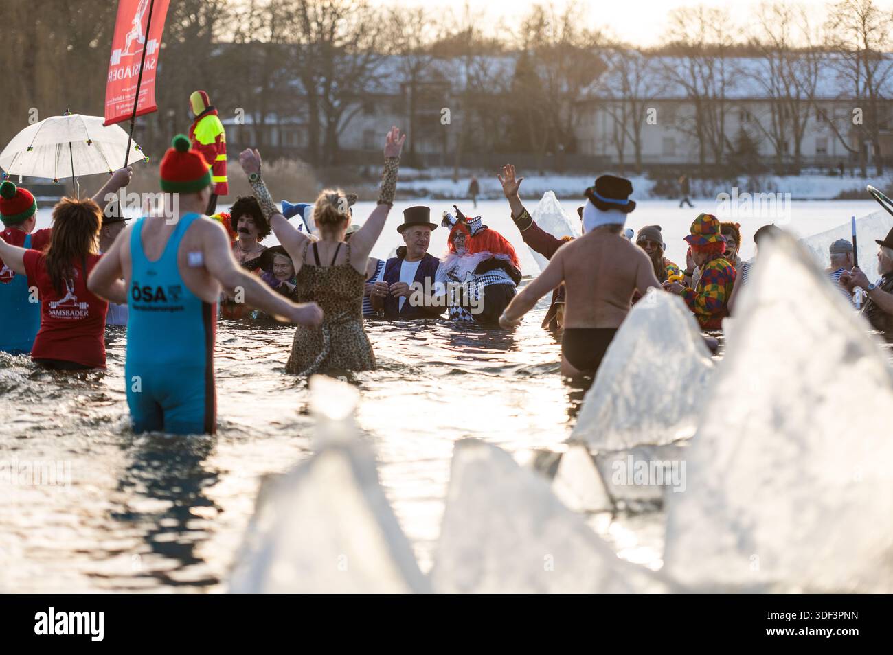 10 January 2026, Berlin: Bathers stand between ice floes in the cold ...