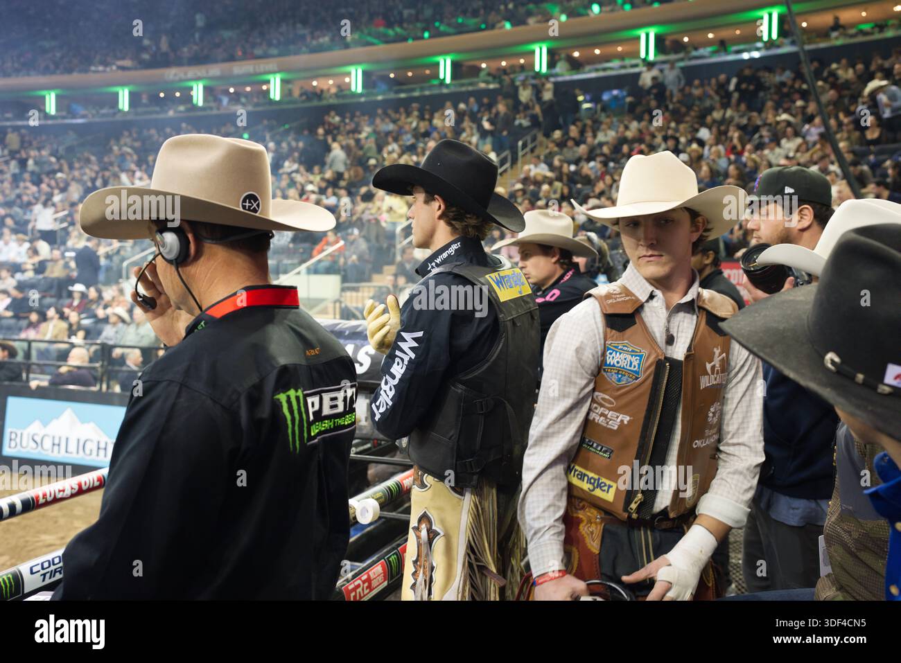 Men in cowboy hats and rodeo attire stand in a stadium, facing away ...