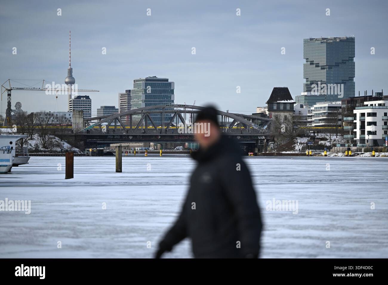 dpatop - 10 January 2026, Berlin: A man stands on the frozen Spree. The ...