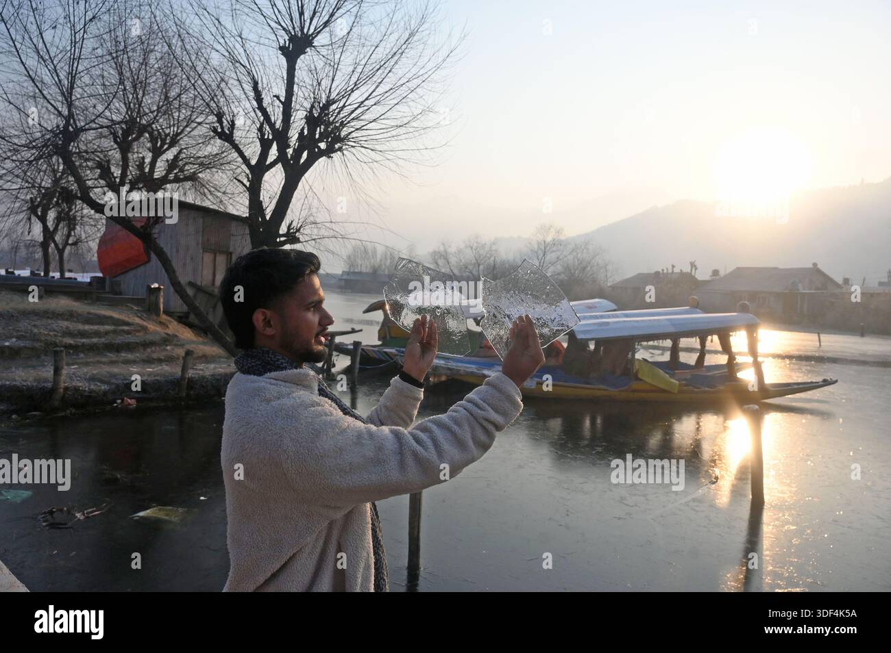 SRINAGAR, INDIA - JANUARY 9: A tourist shows an ice sheet of partially ...