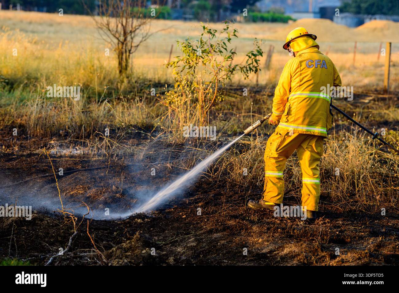 A Country Fire Authority firefighter uses a high pressure hose to ...