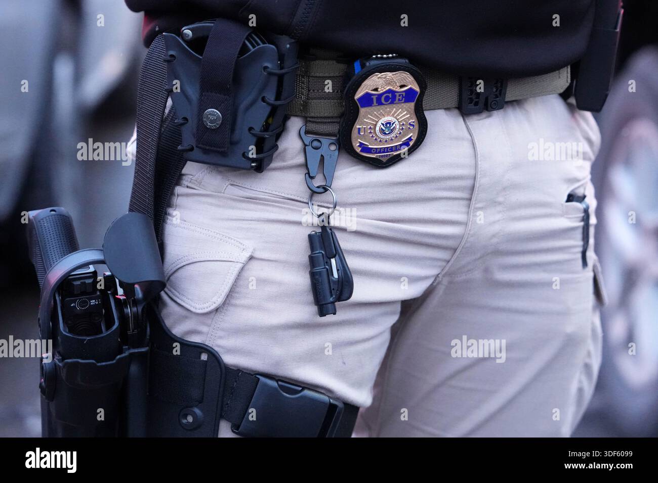 The badge and gun of an ICE officer is seen as a person is detained ...