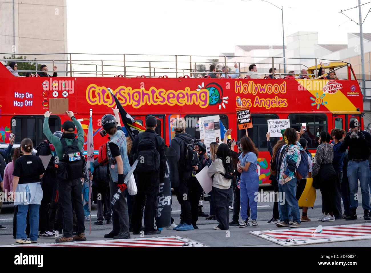 Protesters watch a sightseeing bus go by during a demonstration calling ...