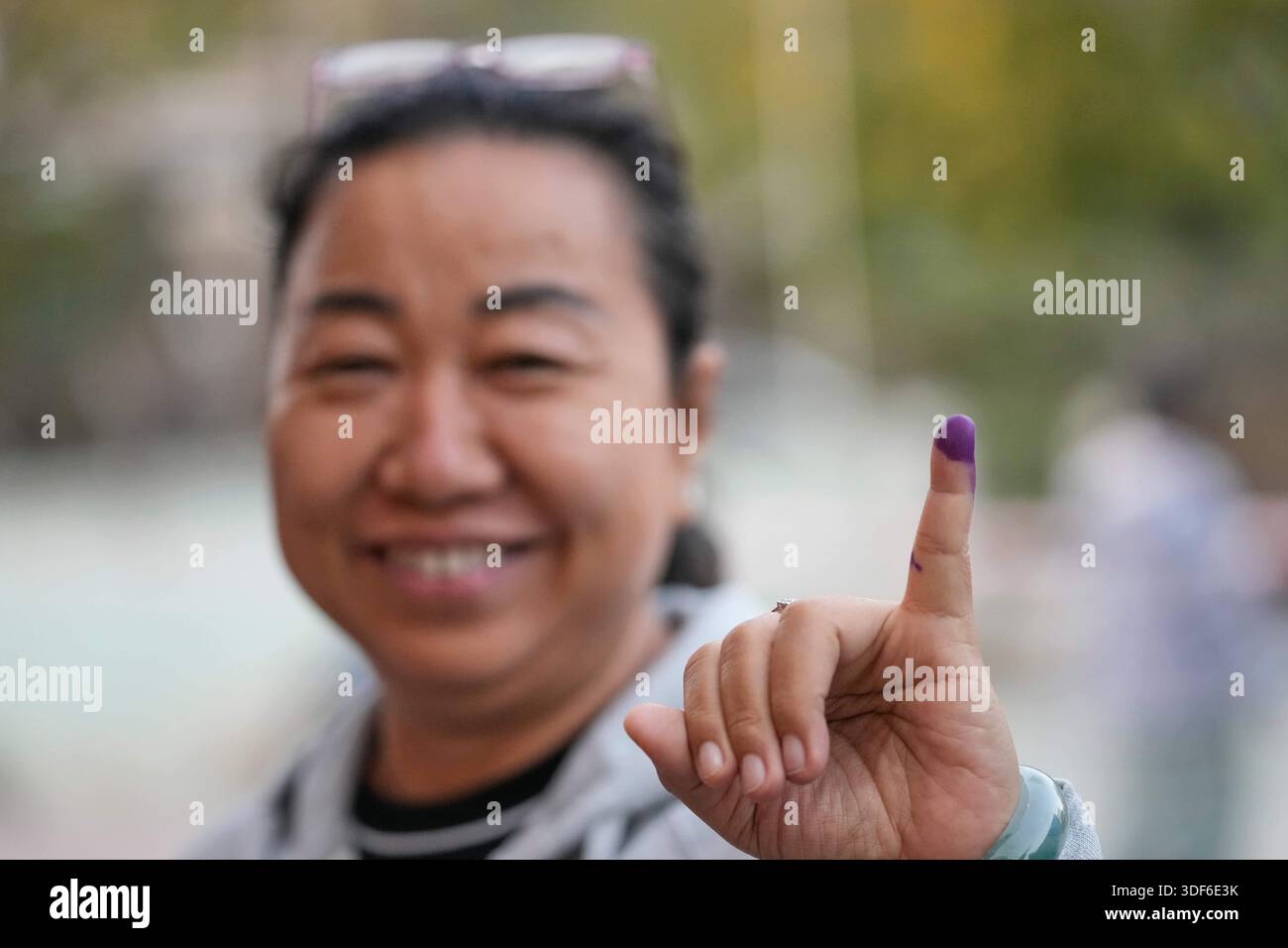 A voter holds up her finger, marked with ink to indicate she voted, at ...