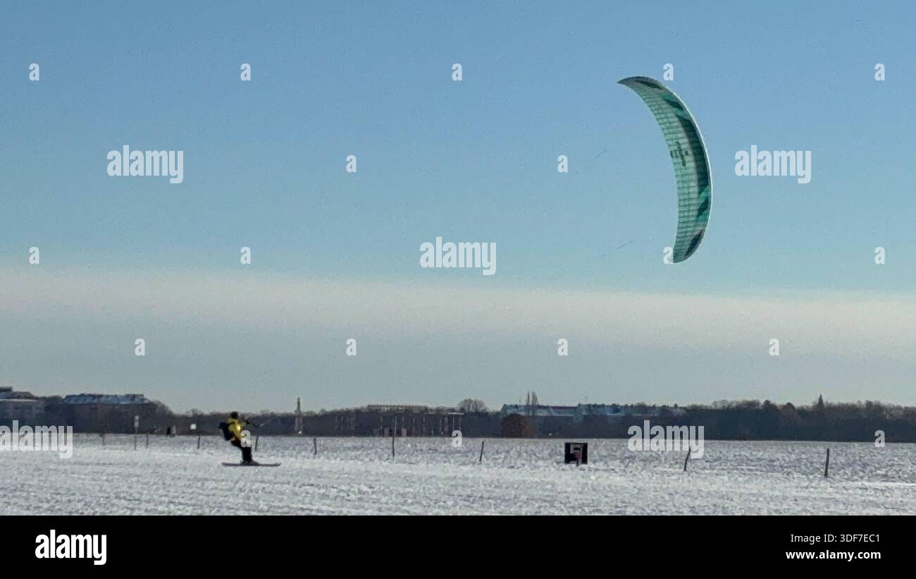 11 January 2026, Berlin: A kitesailor on skis on the snow-covered ...