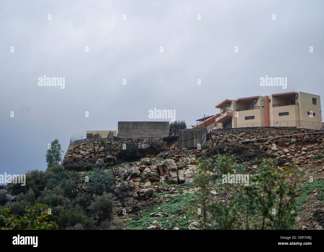 Traditional Cretan stone house built on a rugged rocky hillside under a ...