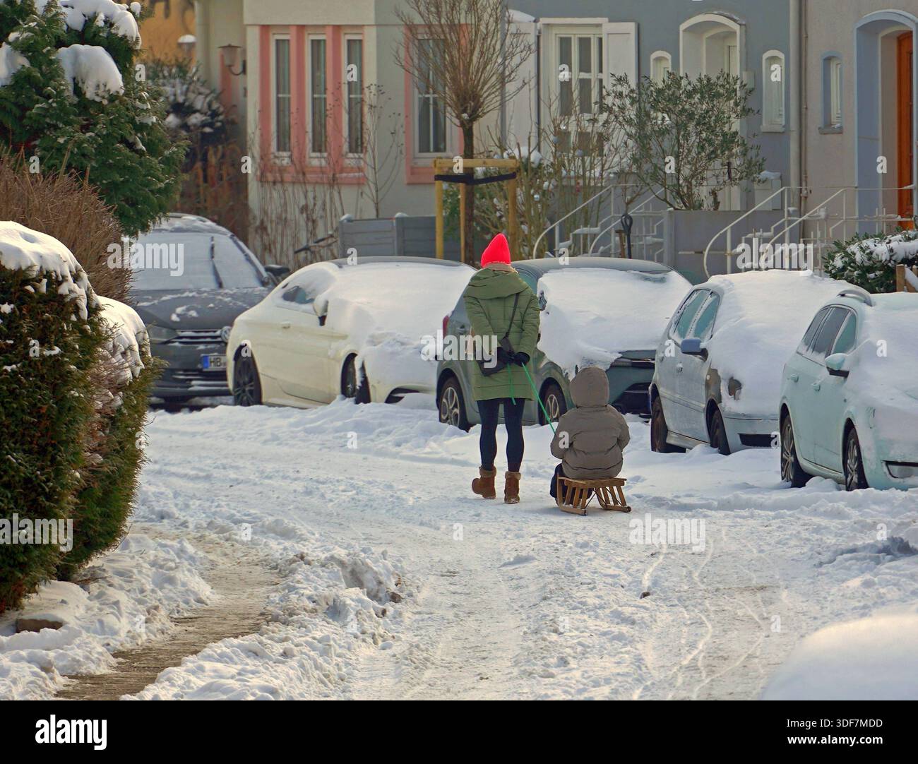 Eine Frau zieht ein Kind auf einem Schlitten auf einer zugeschneiten ...