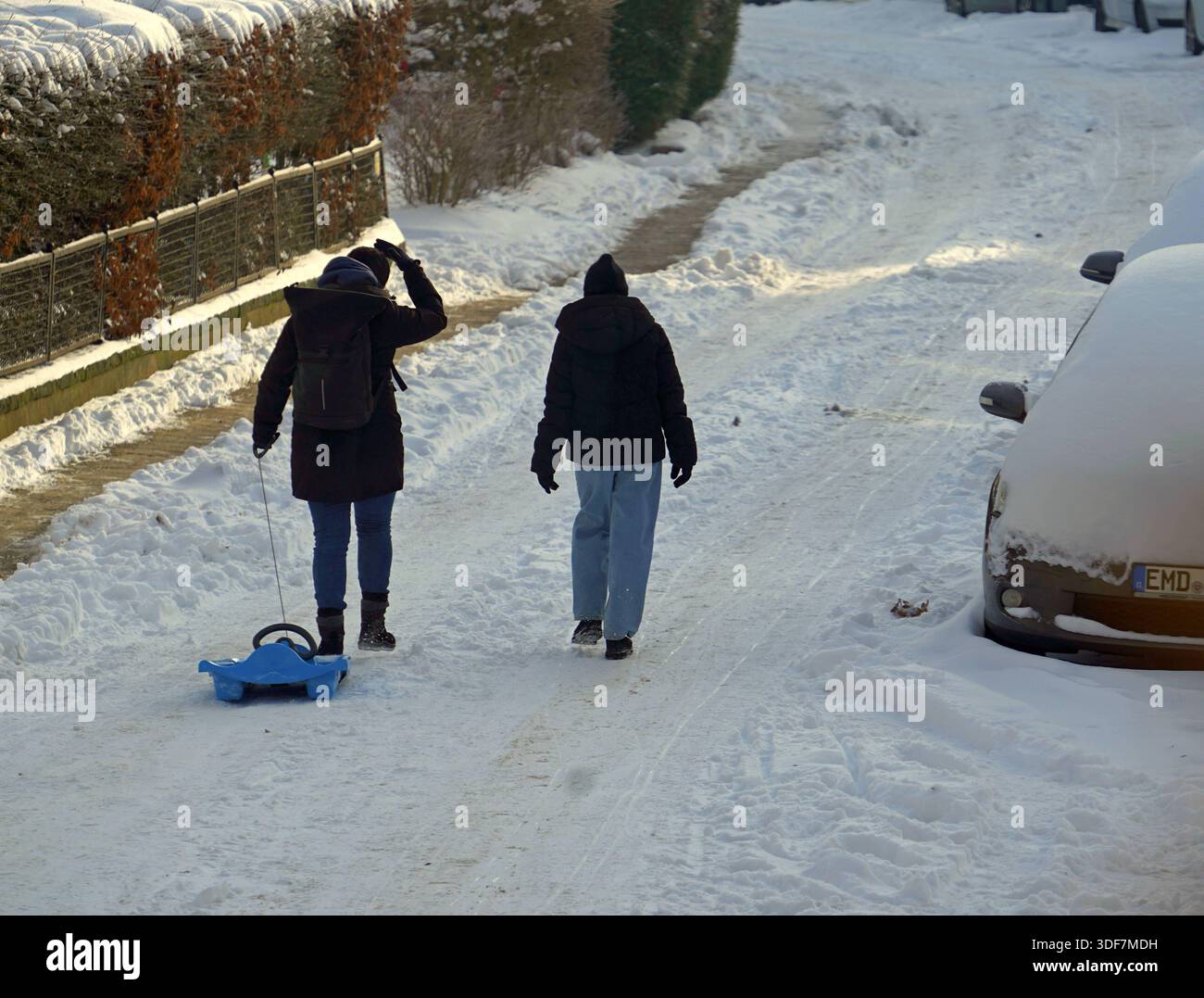 Junge Leute mit Schlitten auf einer zugeschneiten Straße in Bremen ...