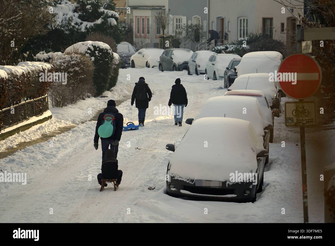 Junge Leute mit Schlitten auf einer zugeschneiten Straße in Bremen ...