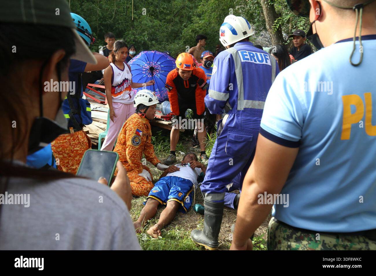 Rescuers attend to a family member who collapsed as he waits for ...