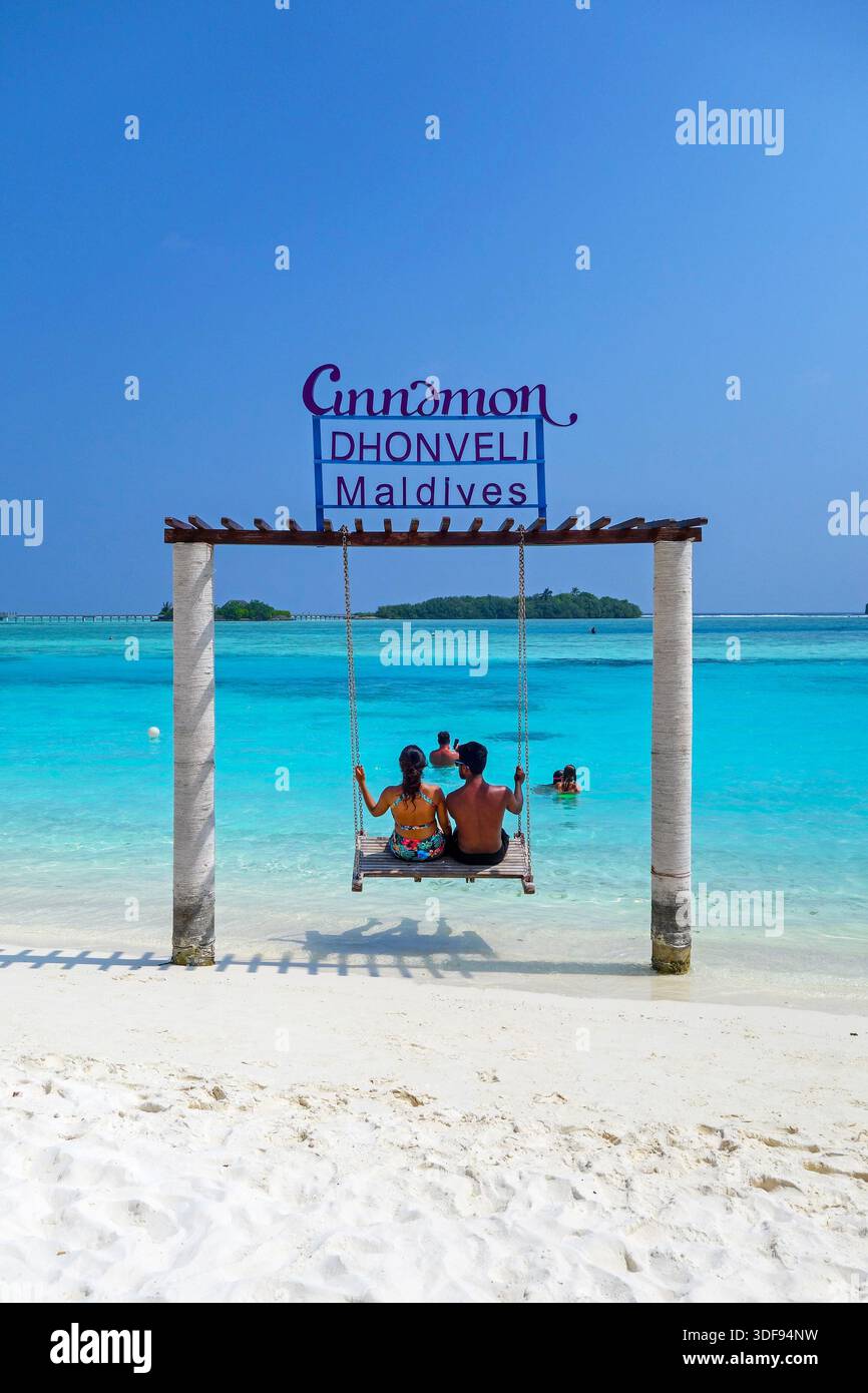 A couple on a swing seat on the beach at the Cinnamon Dhonveli holiday ...