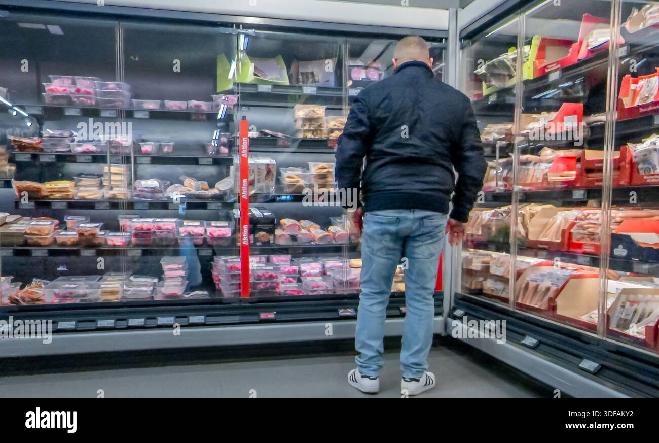 16 December 2025, Hamburg: A customer looks at plastic-wrapped sausages ...