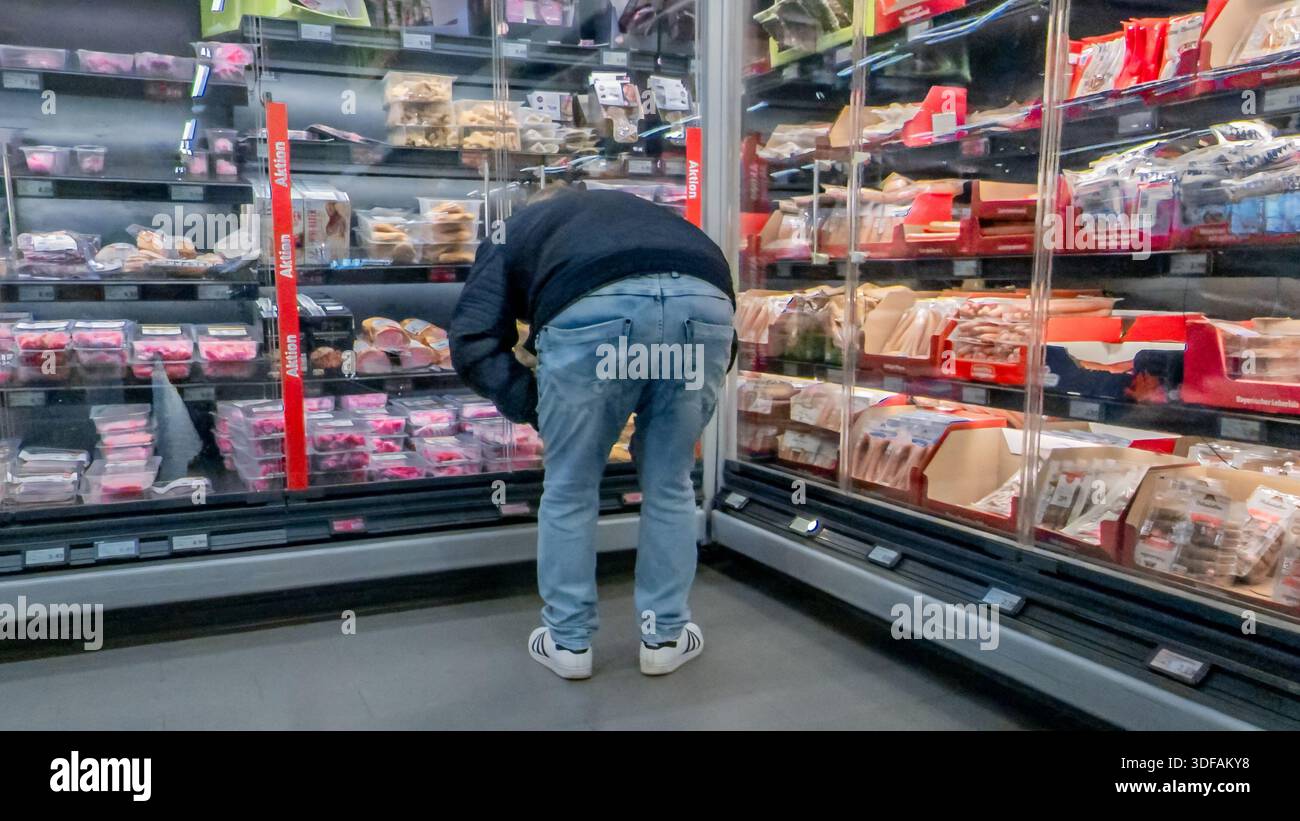 16 December 2025, Hamburg: A customer looks at plastic-wrapped sausages ...