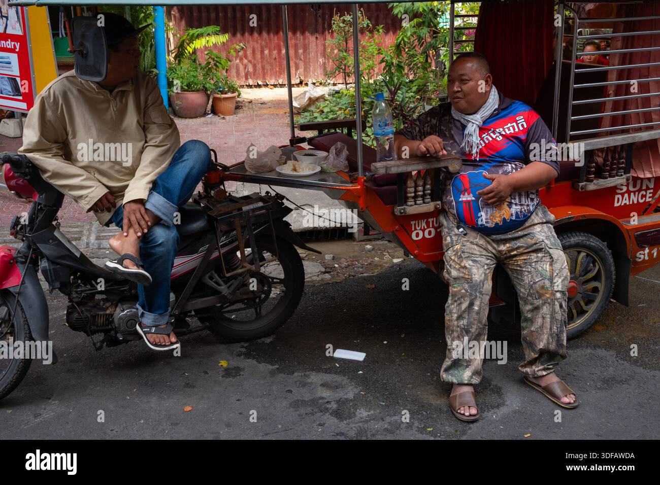 January 11, 2026, Phnom Penh, Cambodia: Men chat beside a remorque, a ...