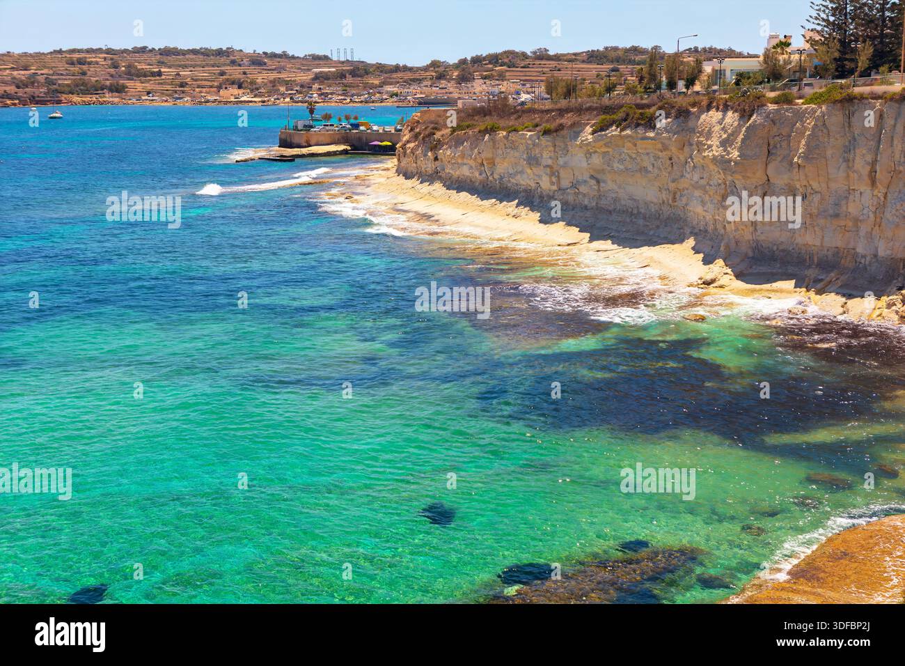 Clear blue waters and limestone cliffs of Saint Thomas Bay in Malta, a ...
