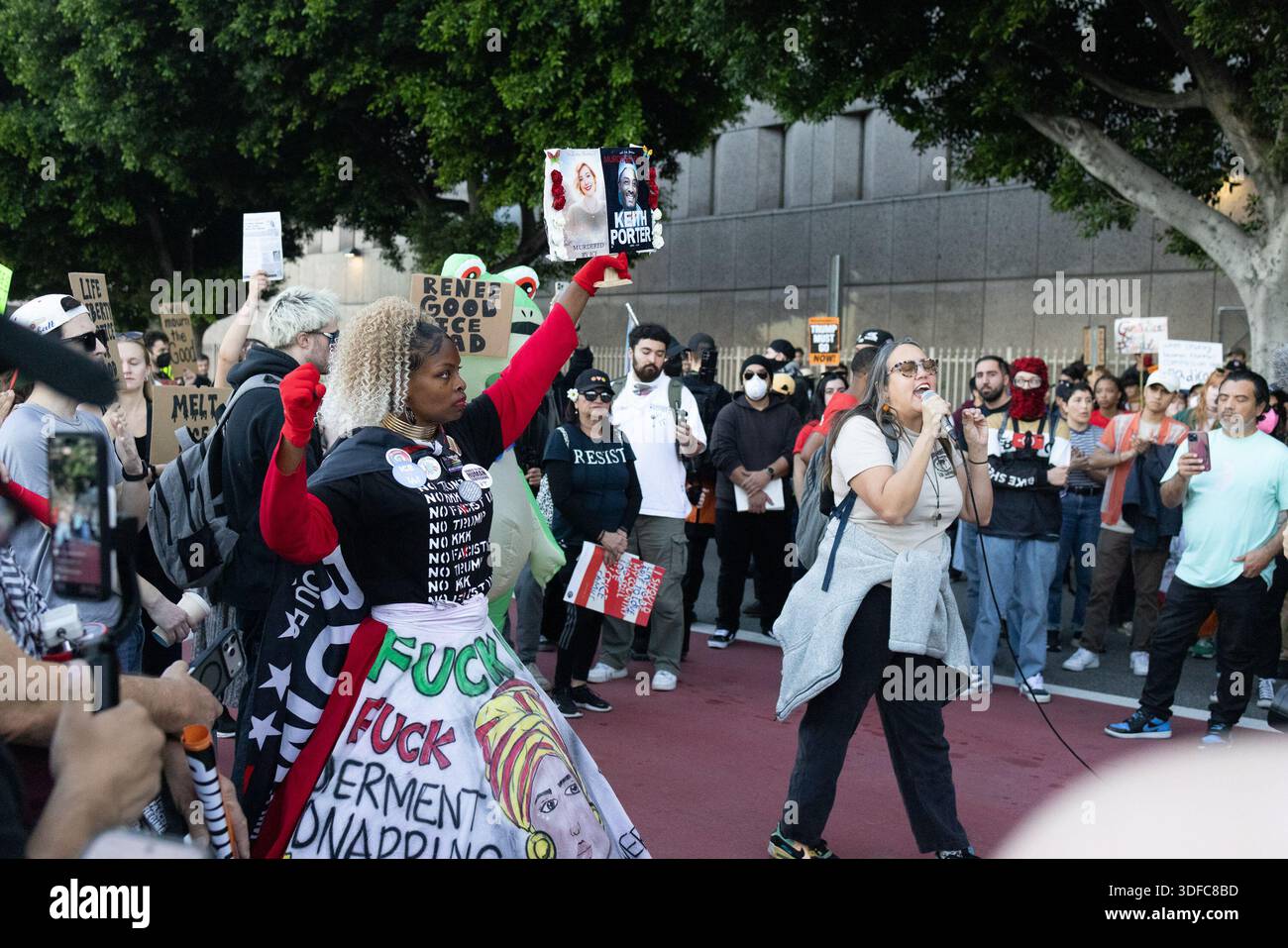 A protester raises her fist and holds portraits of Renee Nicole Good ...
