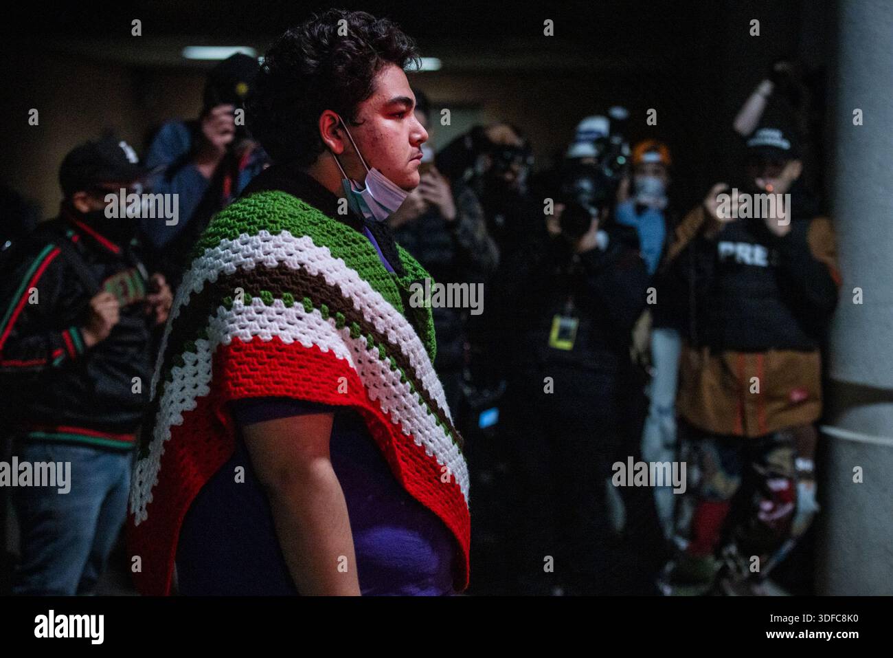A protester stands facing the Metropolitan Detention Center as a line ...