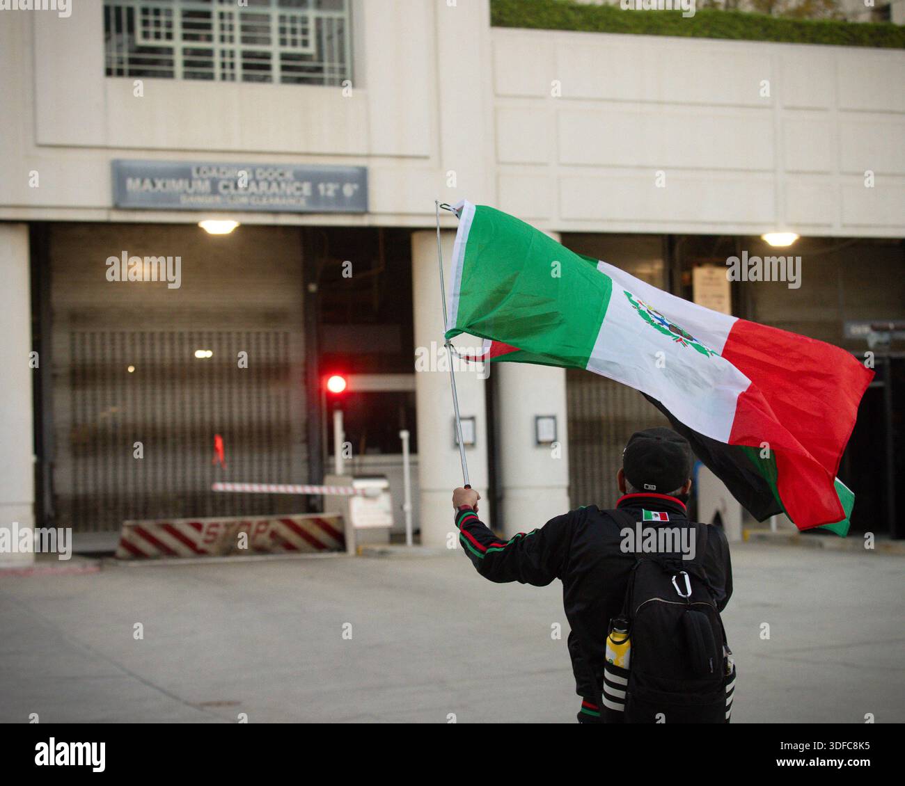 A lone protester waves a Mexican flag near the gates of the ...