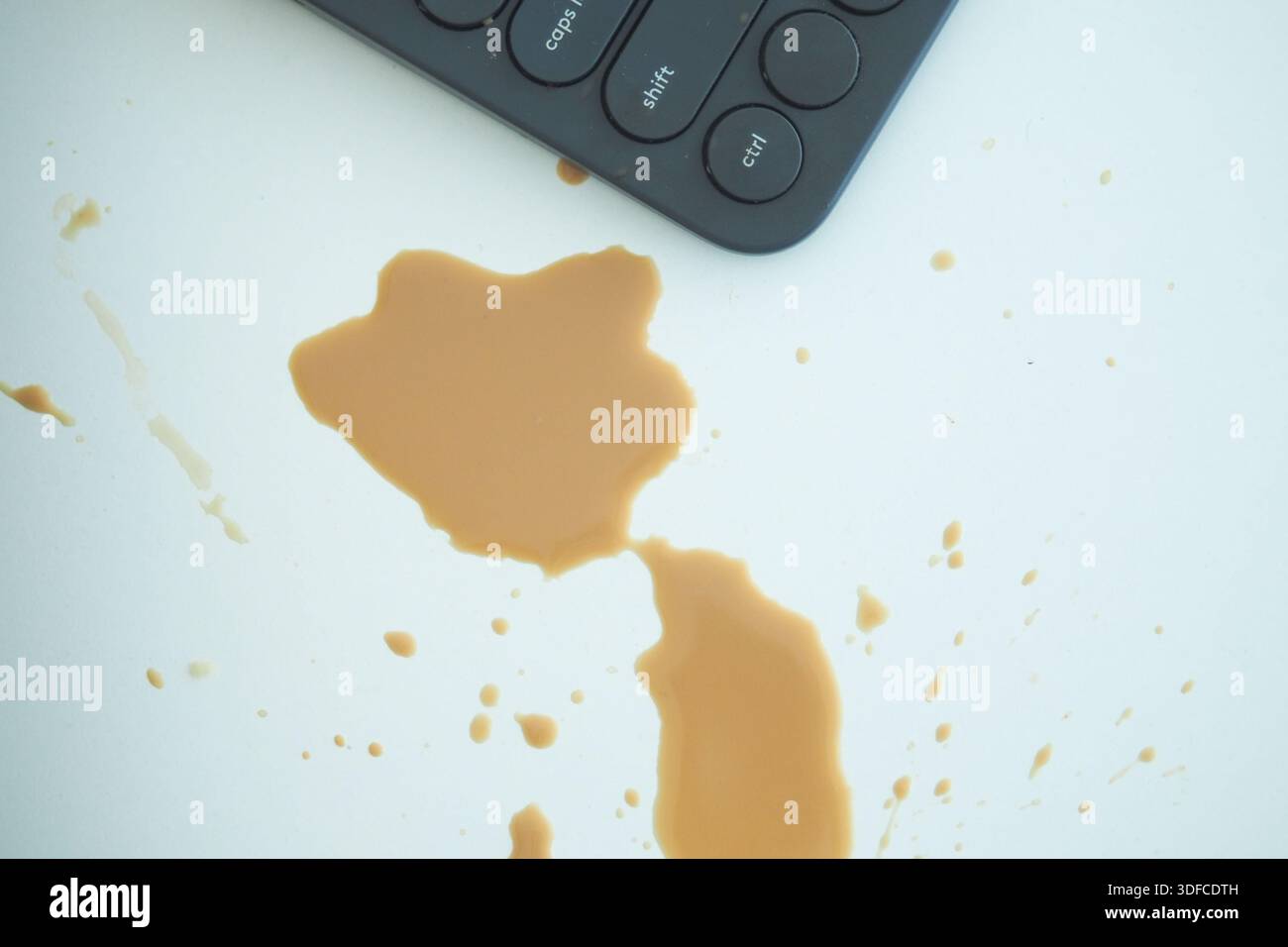 Coffee spill near keyboard on a white table surface Stock Photo - Alamy