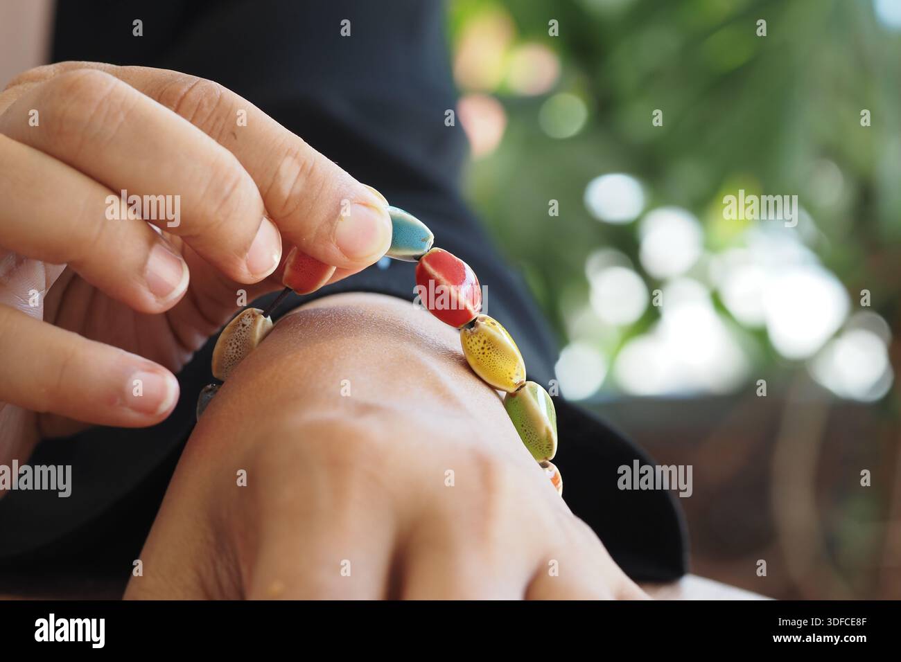 Person puts colorful bracelet on wrist during daylight Stock Photo - Alamy