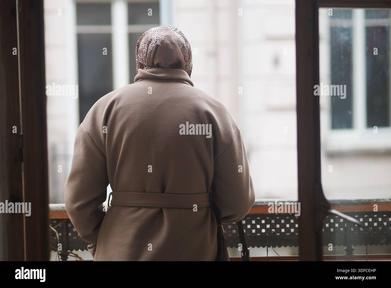 Woman stands by window looking outside during the day Stock Photo - Alamy