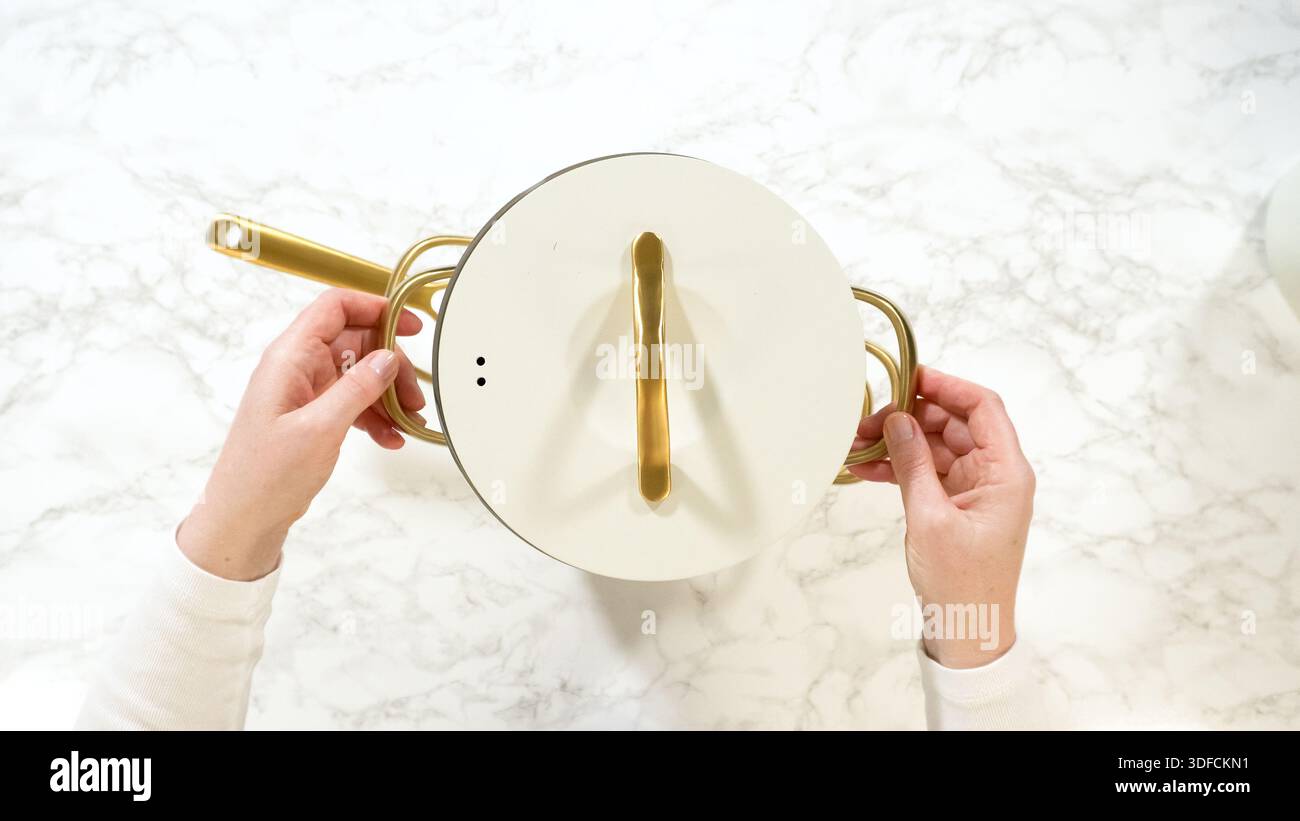 Lifting lid on golden handle cooking pot Stock Photo - Alamy