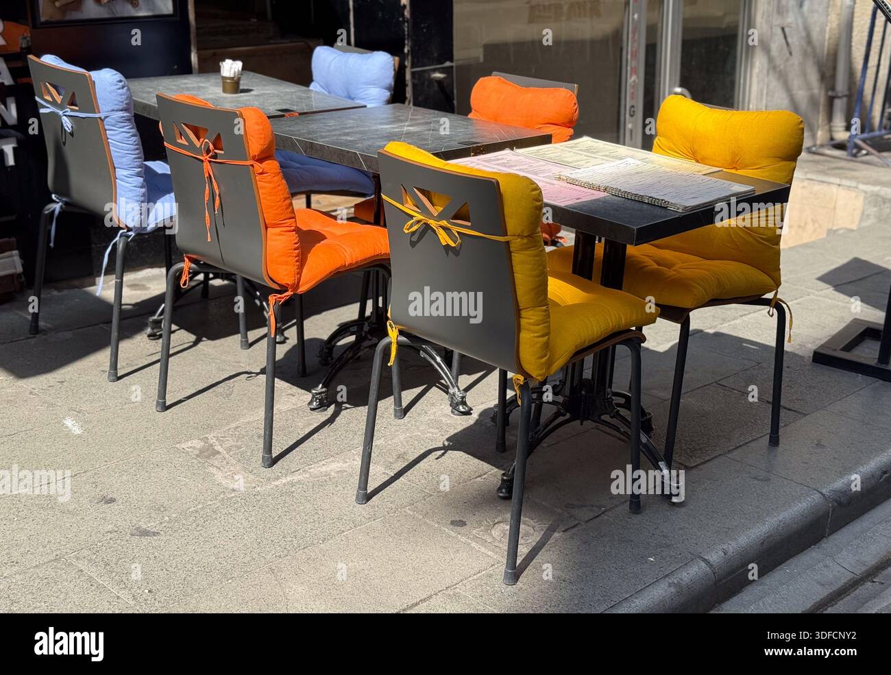 Outdoor cafe with wooden chairs, marble tables, and bright yellow ...