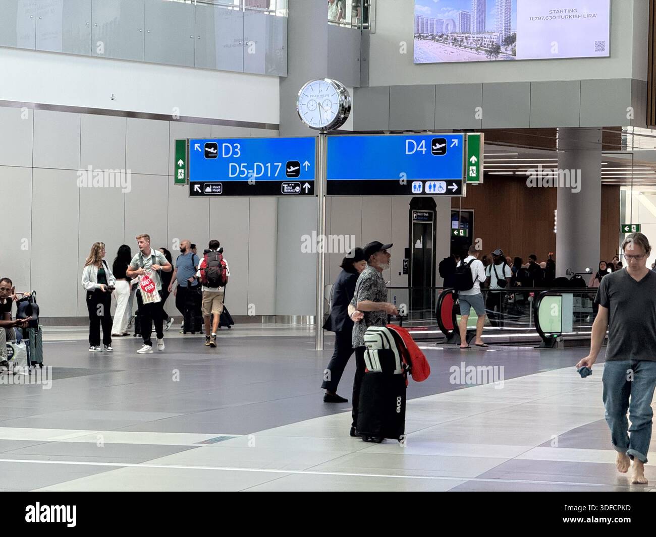 Passengers walking beneath directional signs and central clock inside ...