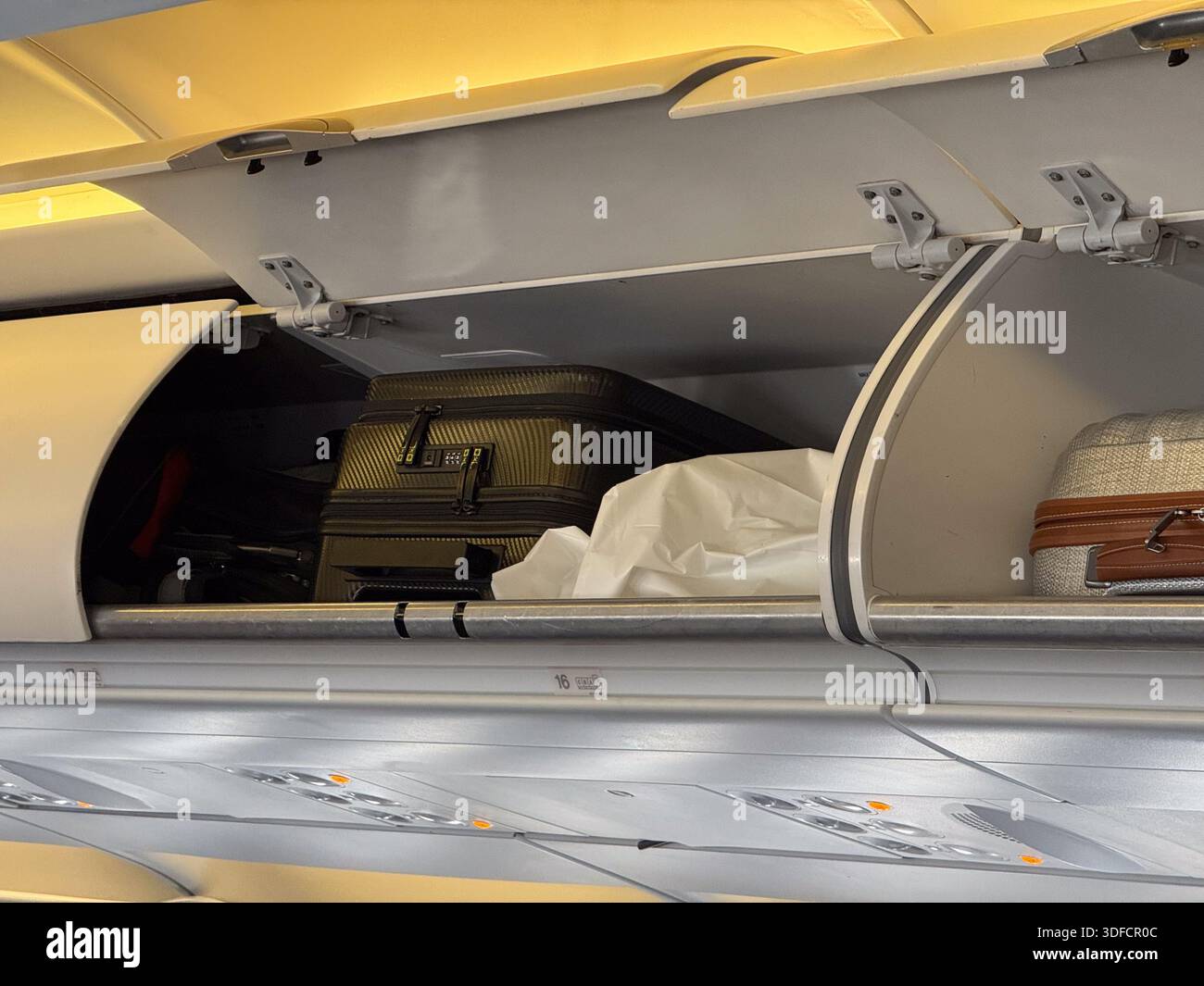 Overhead storage bins inside airplane cabin with luggage and personal ...