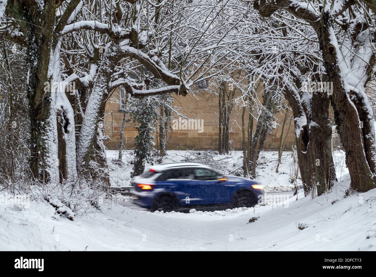 12 January 2026, Bavaria, Neubanz: A car drives past a snow-covered ...