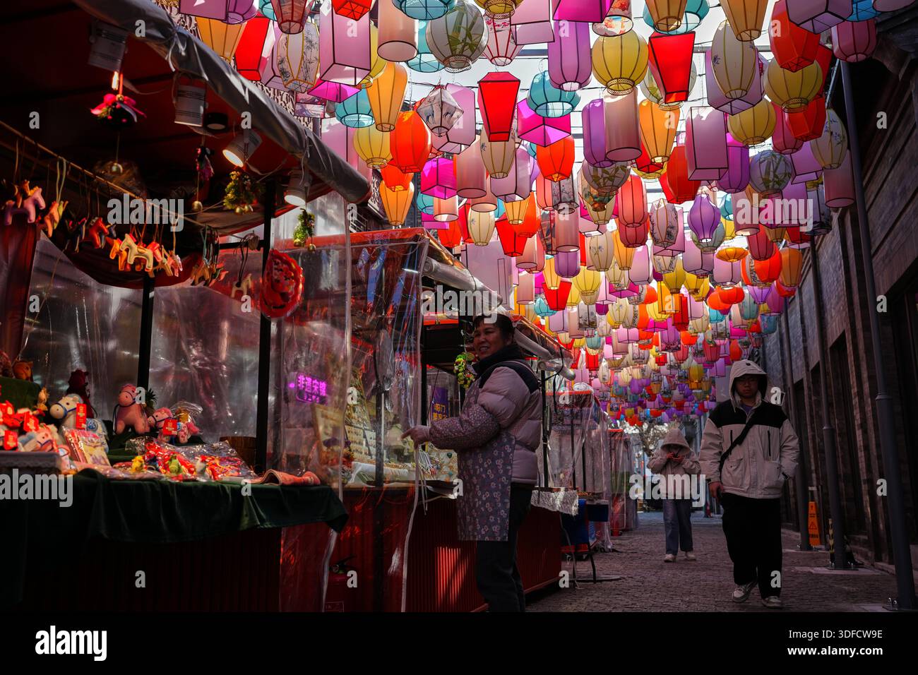 Tourists walk past a vendor seting up her store selling souvenirs at ...