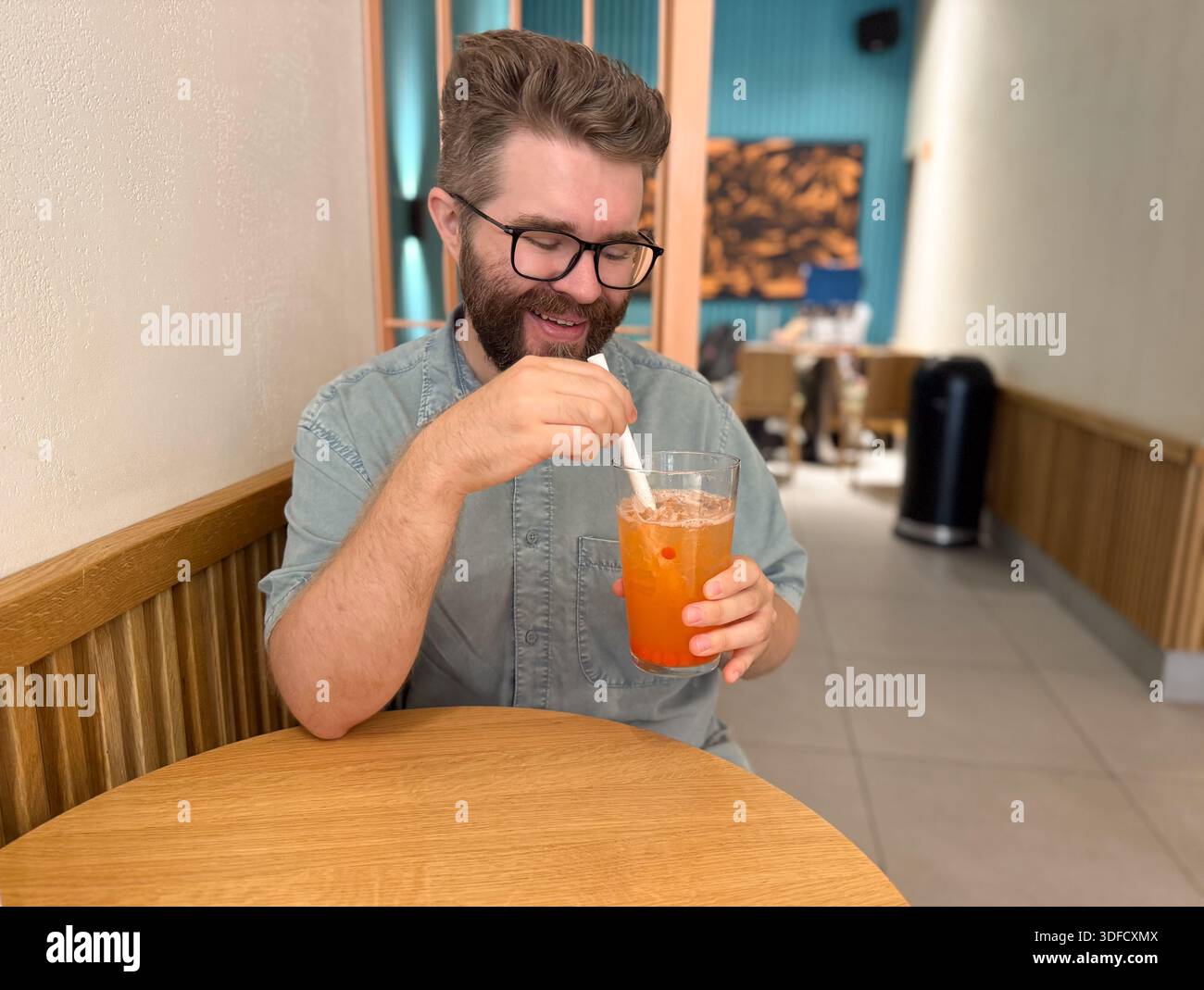Man enjoying iced fruit tea at wooden cafe table. Relaxed mood ...