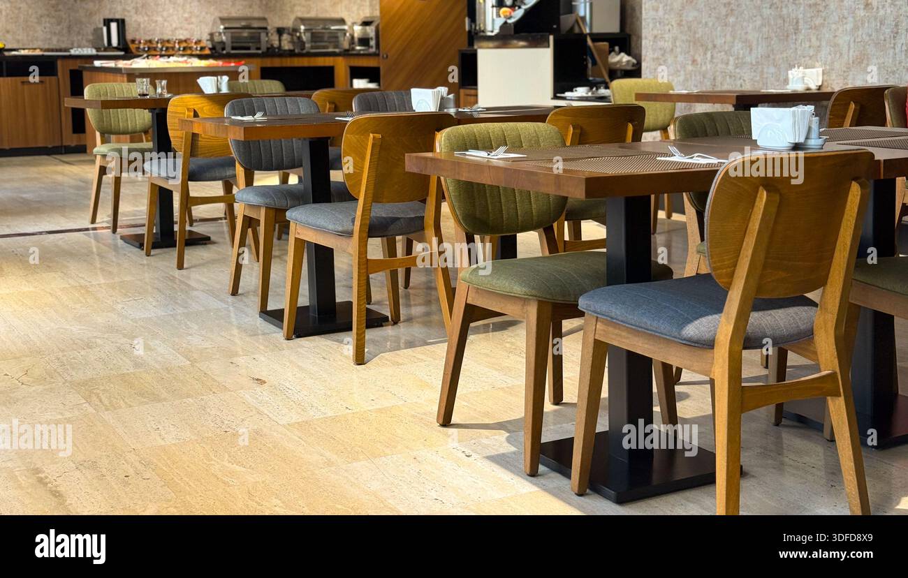 Empty hotel restaurant dining area with wooden tables and upholstered ...