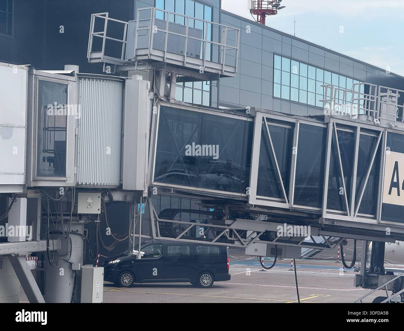 Airport jet bridge and terminal facade with service vehicle. Ground ...