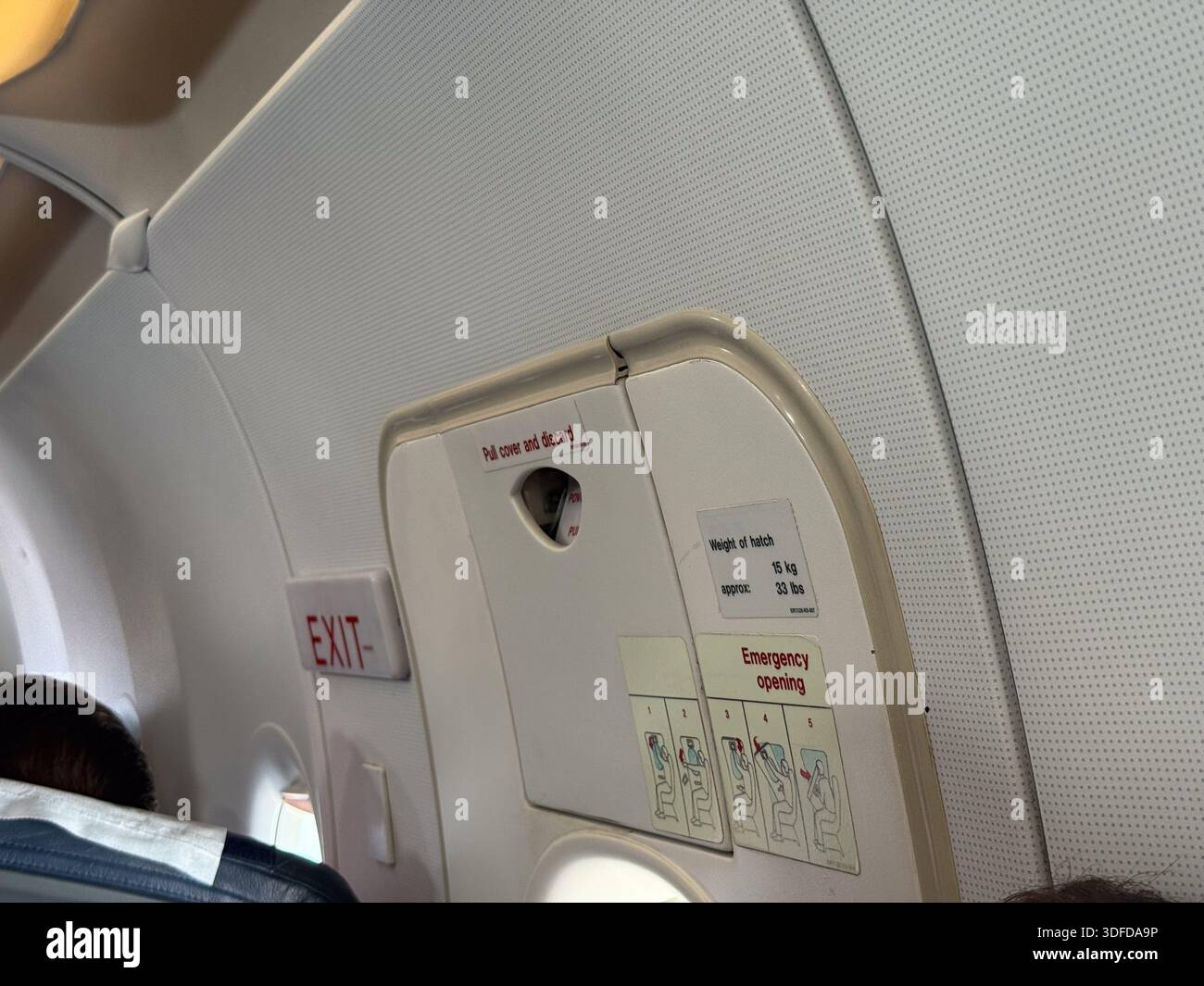 Emergency exit door and safety instructions inside aircraft cabin ...